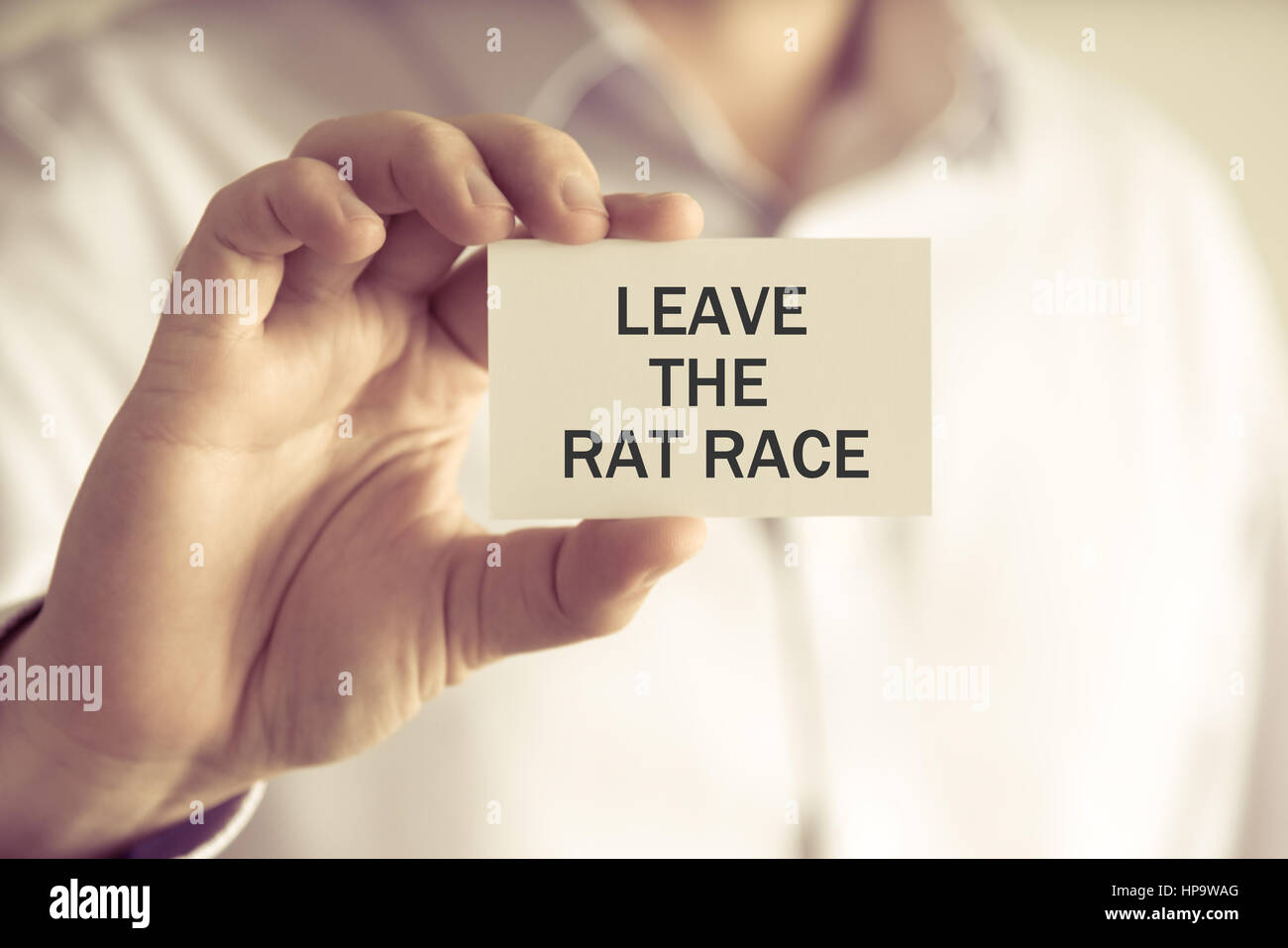 Closeup on businessman holding a card with text LEAVE THE RAT RACE ...