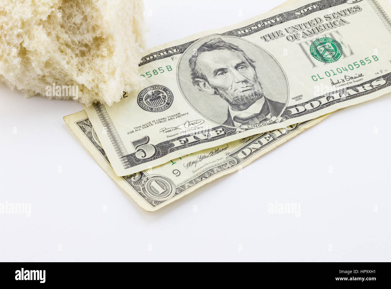 Piece of bread and dollar bills on white background - Conceptual image ...