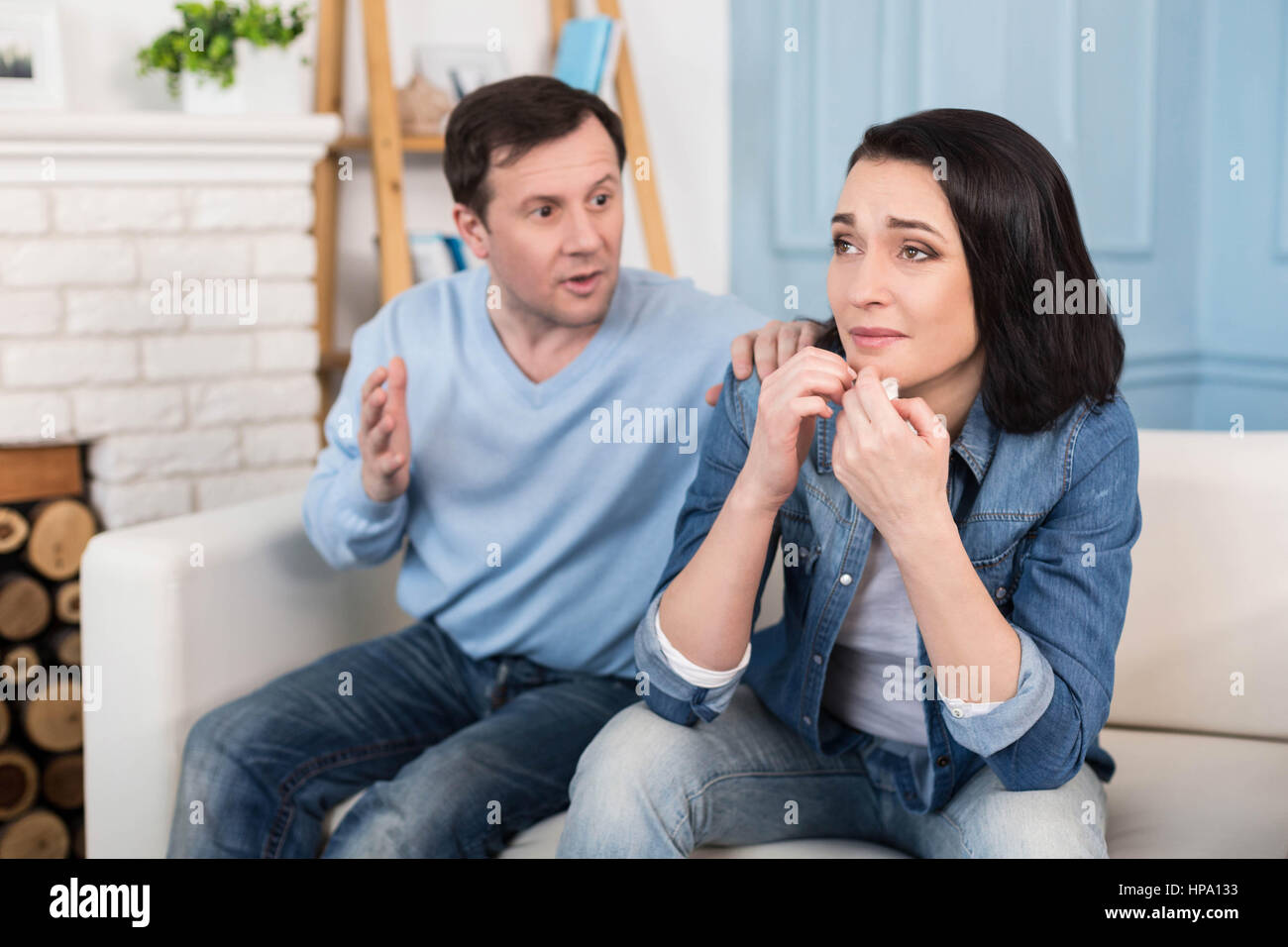 Negative emotions. Miserable upset pretty woman sitting on the sofa and ...