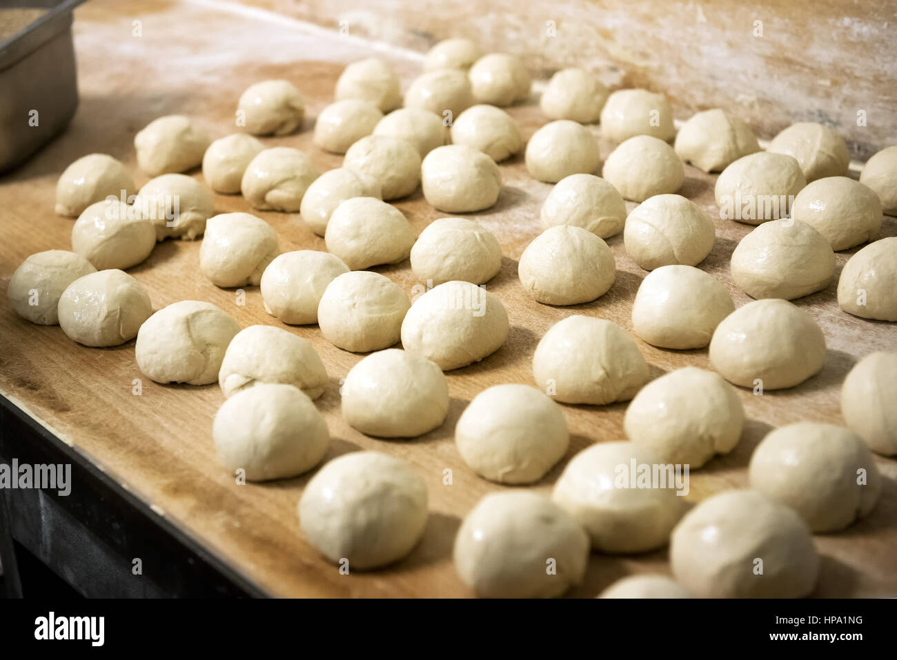 Close-up of many small lumps of dough for bread on wooden bakers table ...