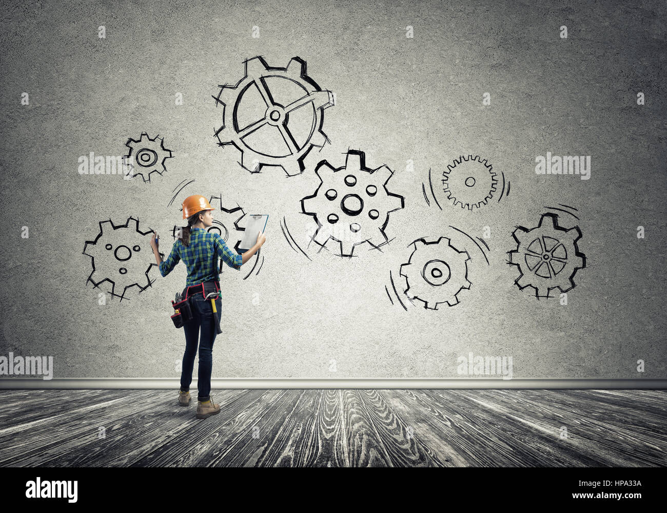 Back view of engineer woman in hardhat and sketched concept of teamwork ...