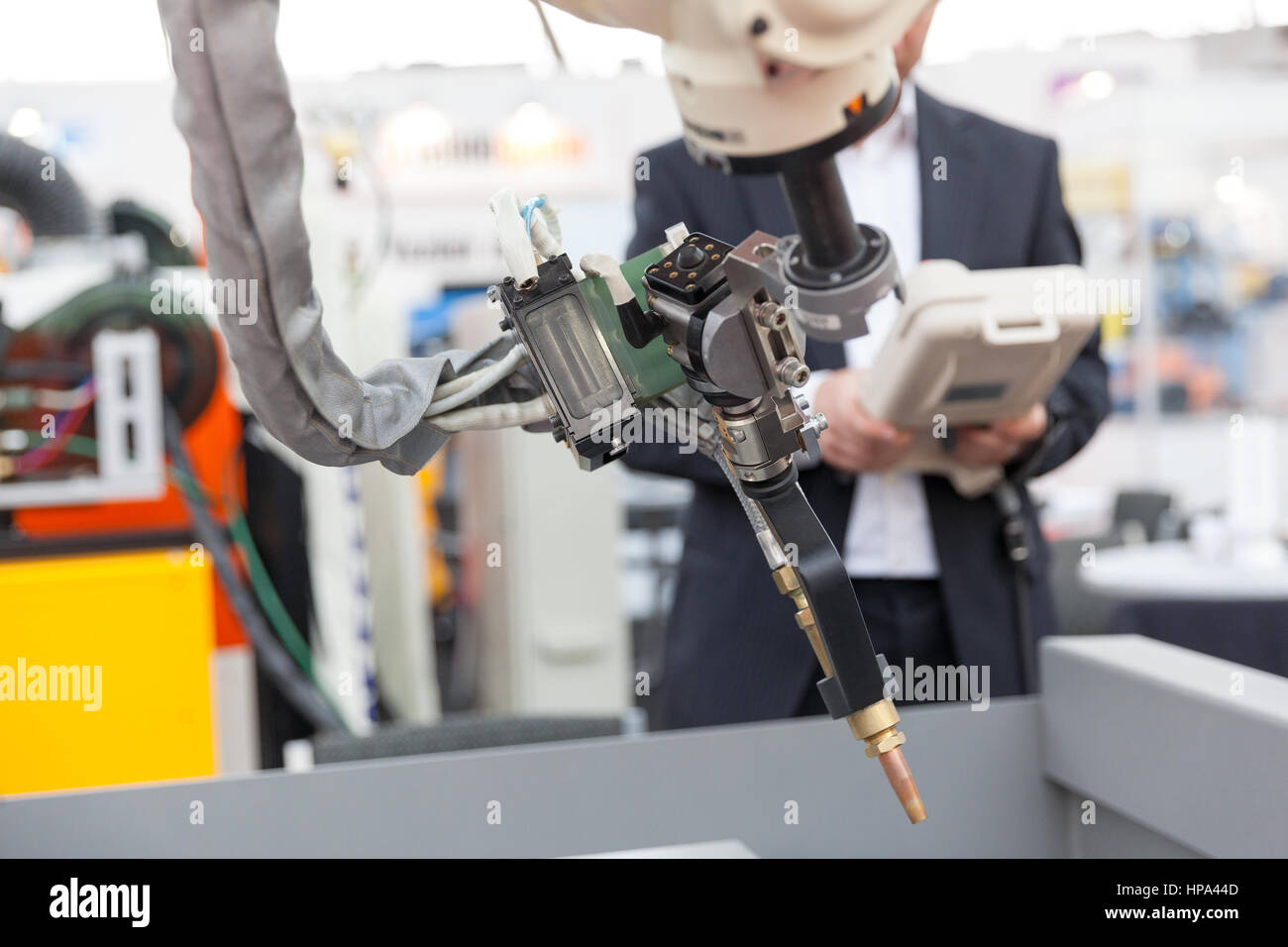 Industrial welding robot arm in the focus, blurred operator in the ...
