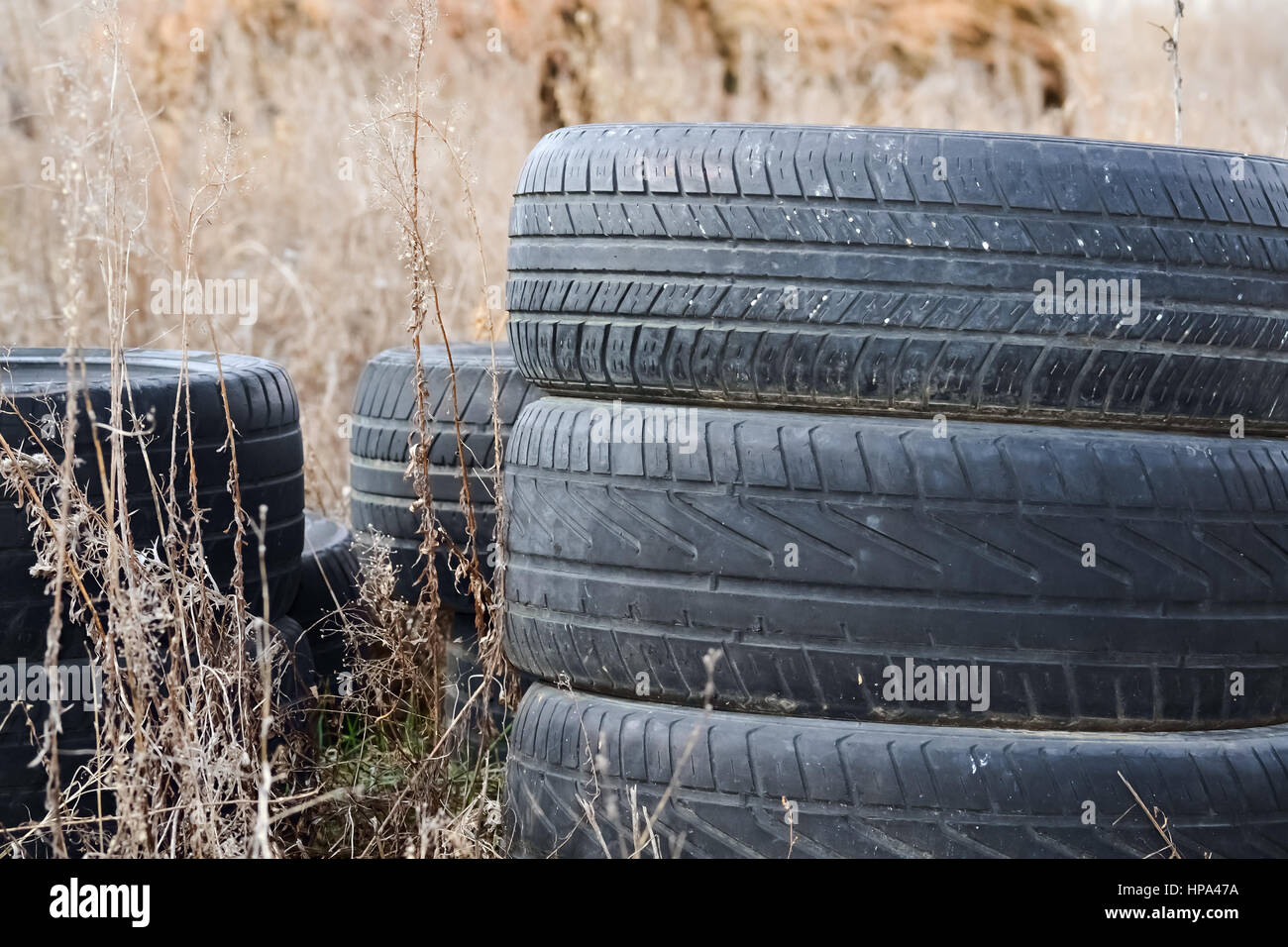 Closeup of several worn tires placed in the grass Stock Photo - Alamy