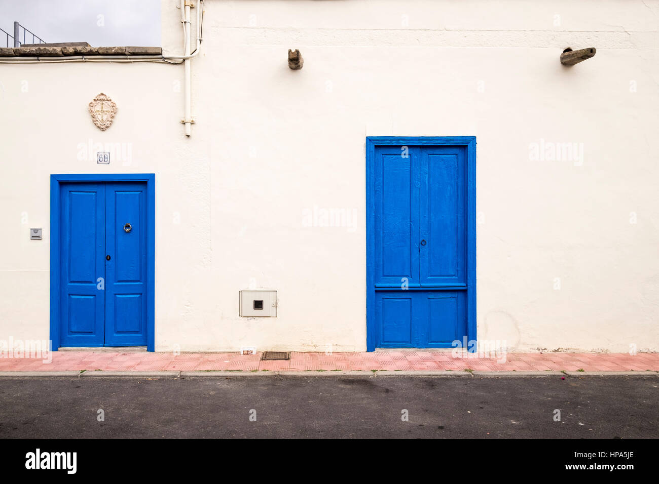 House facade with blue front door and tile house number 63, plaque over ...