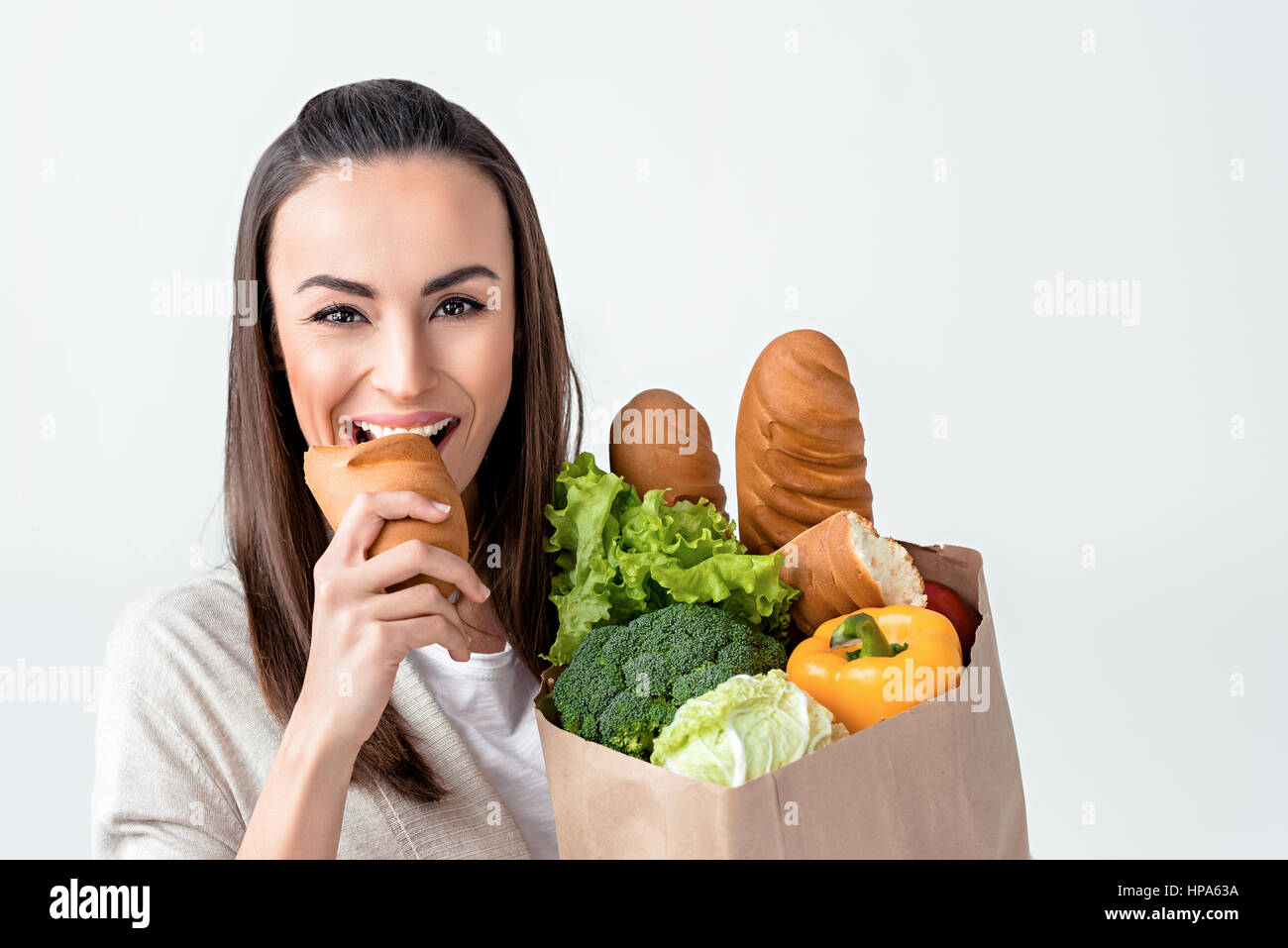 woman with grocery bag biting bread on white Stock Photo - Alamy