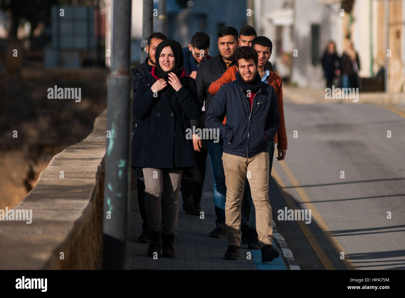 Youngs walk in the streets next to the wall that divide the city of ...