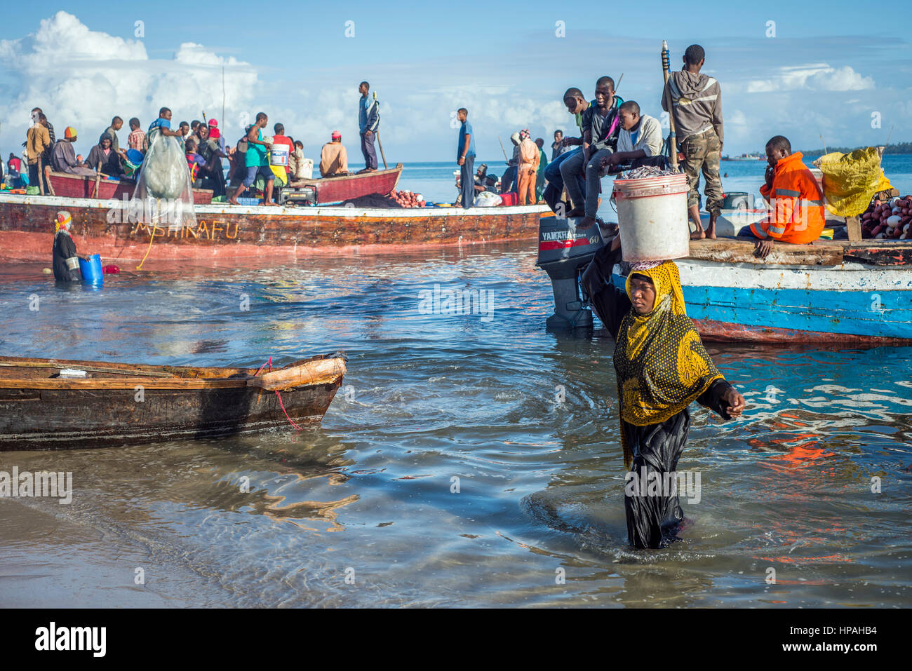 People walk through water with buckets in their hand to buy anchovies ...