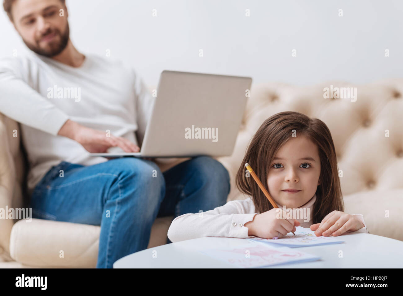 Drawing a picture. Nice delighted pleasant girl sitting at the small ...