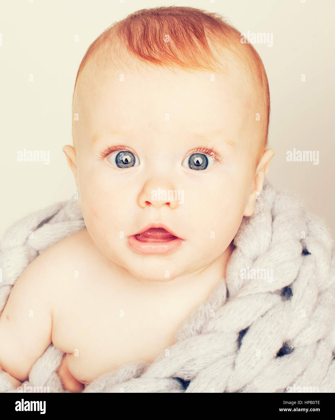 little cute red head baby in scarf all over him close up isolated ...