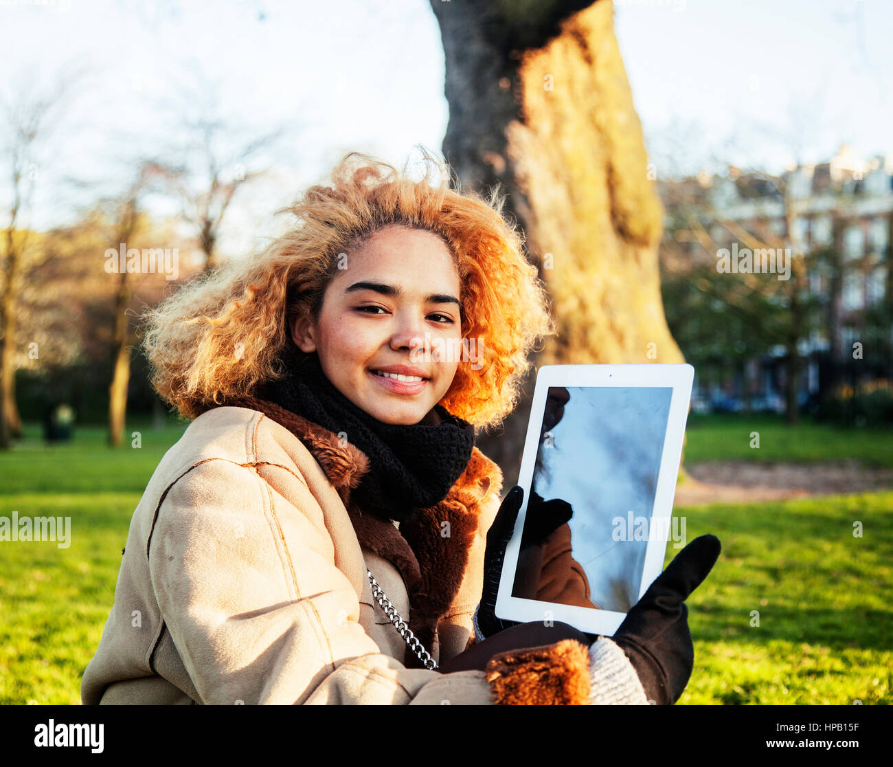 young cute blond african american girl student holding tablet and ...