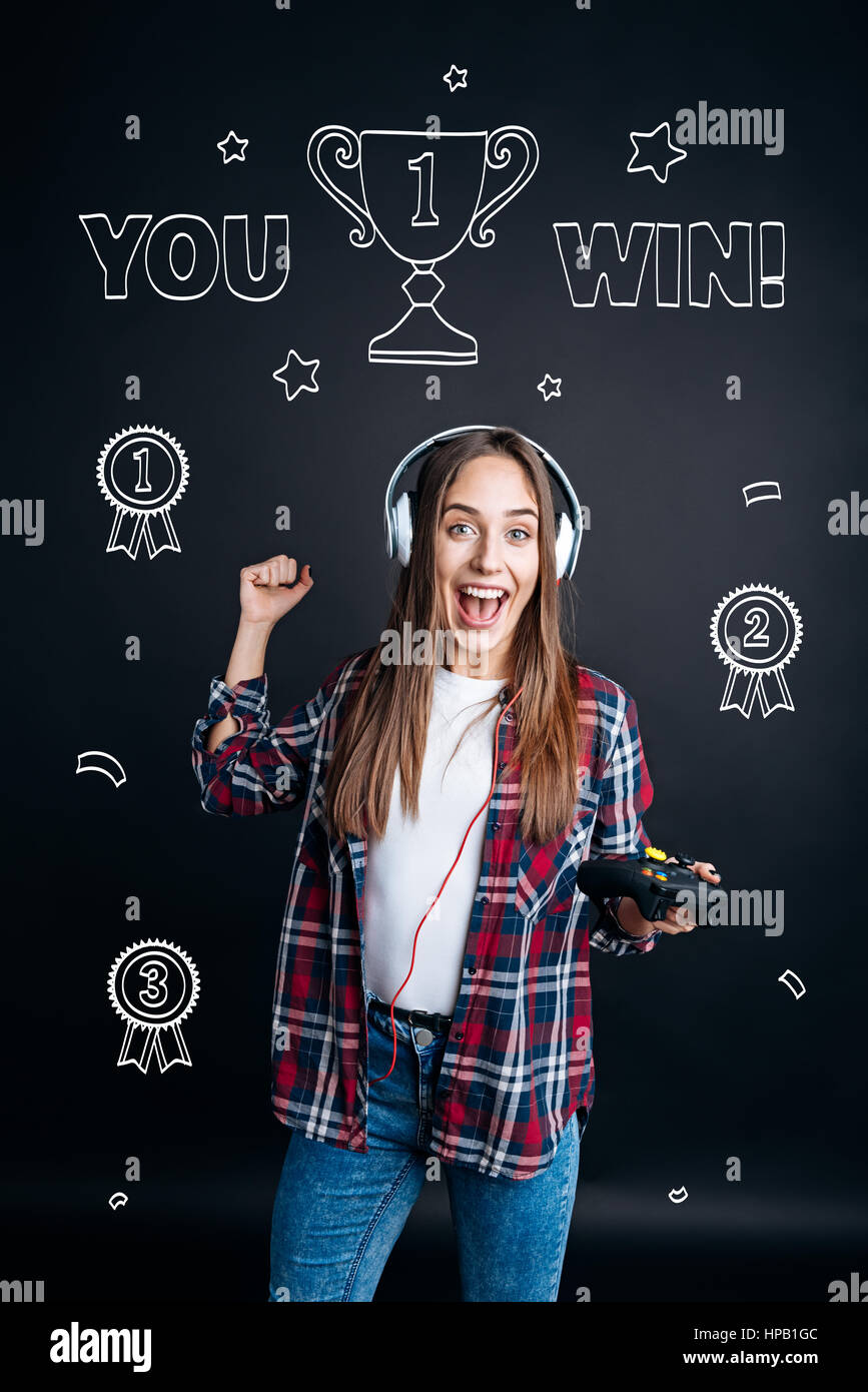My victory. Joyful content young woman smiling and winning a round in ...