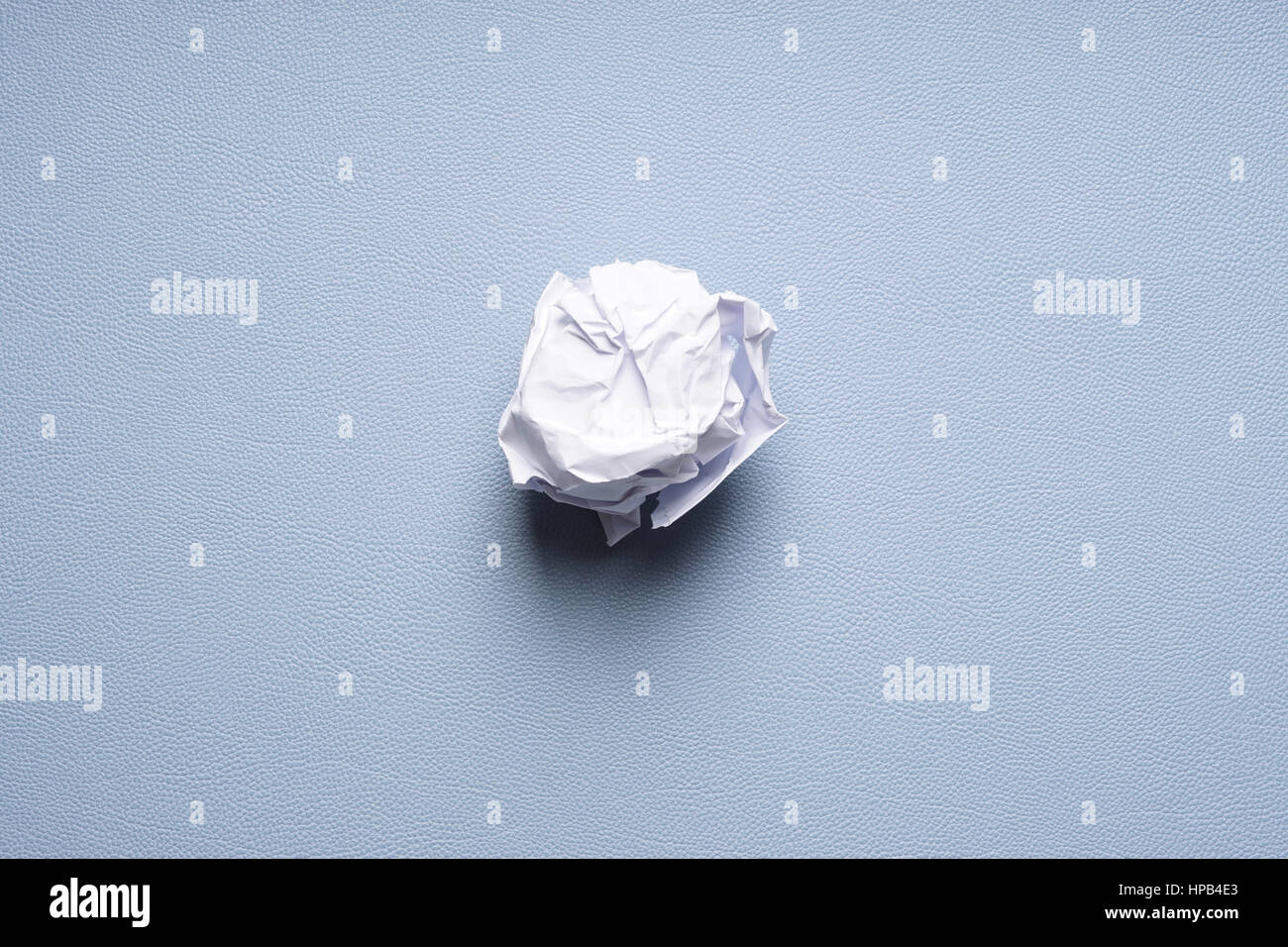 crumpled-up ball of paper on blue background Stock Photo - Alamy