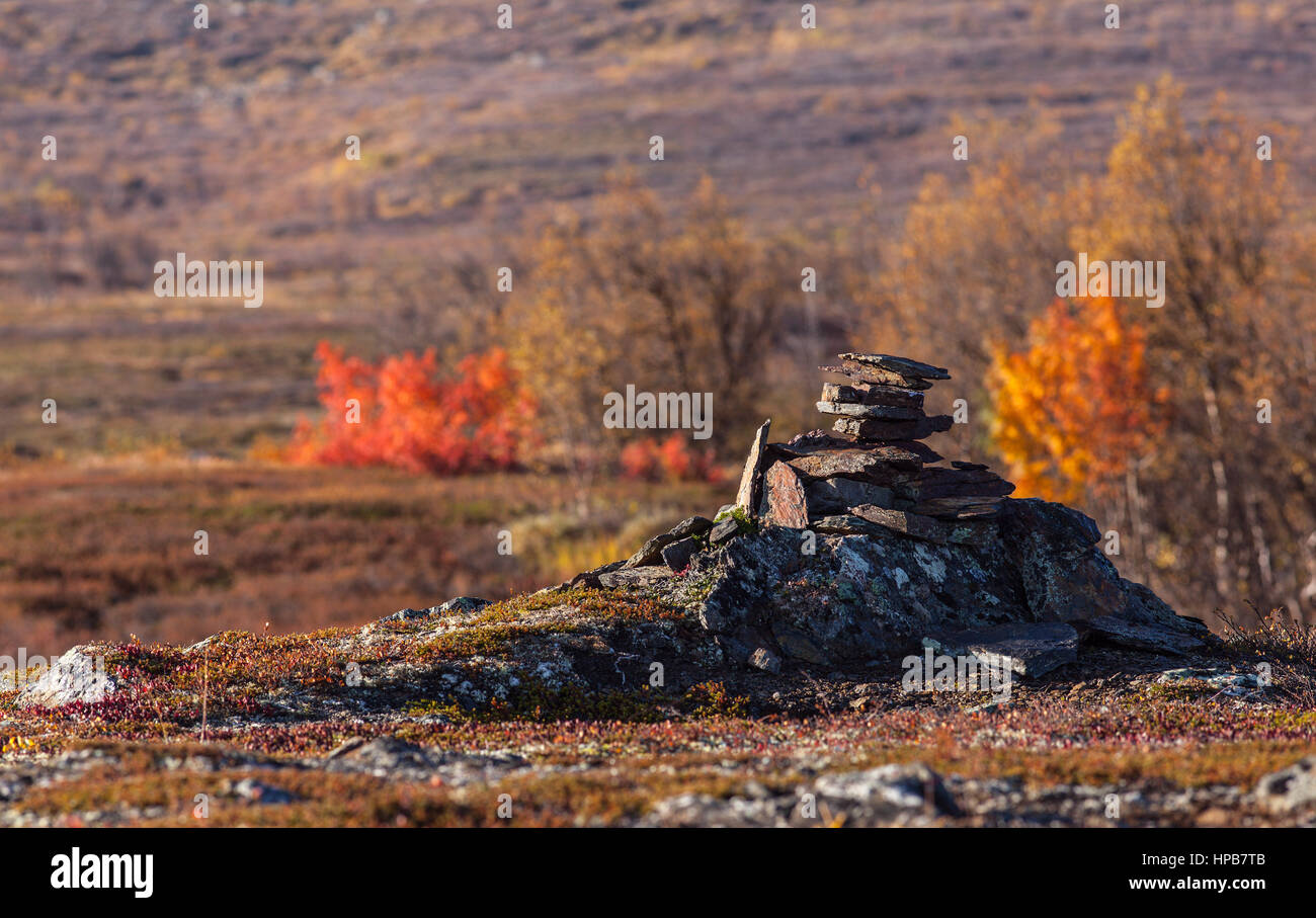 Stack of stones along a mountain trail. Track and colorful bushes in ...
