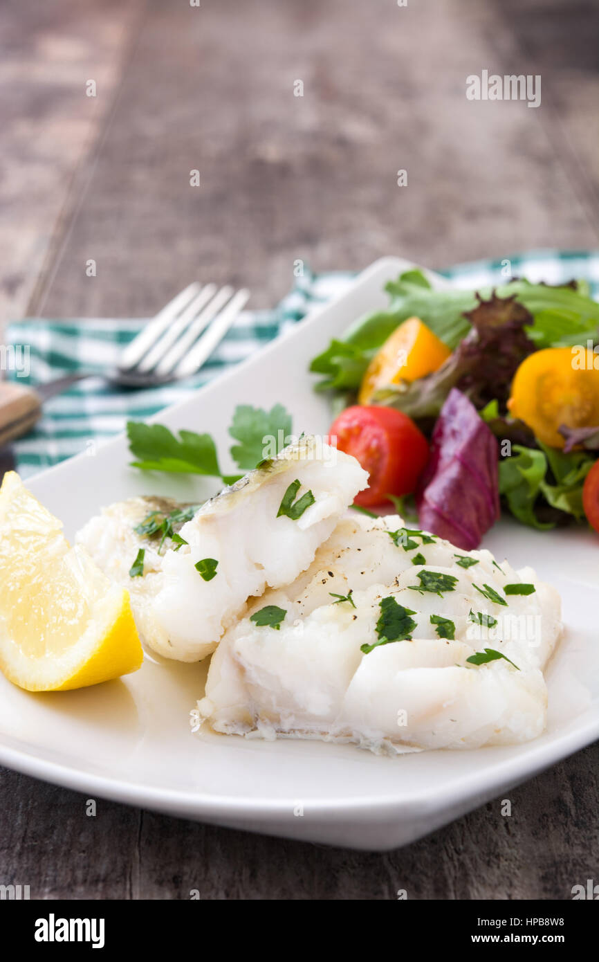 Fried cod fillet and salad in plate on wooden background Stock Photo ...