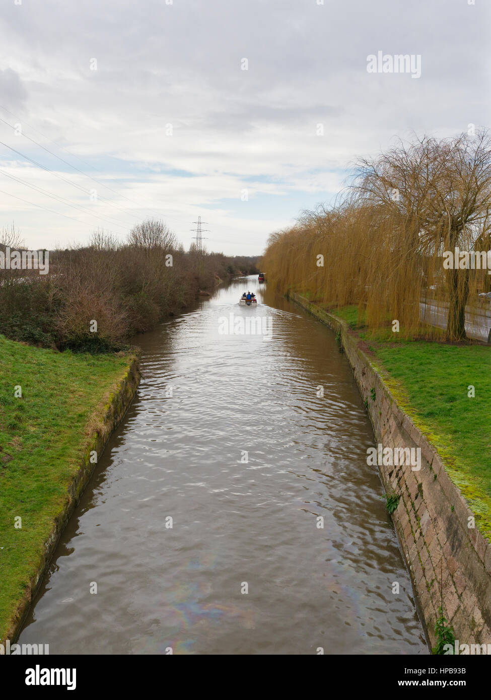 A distant boat sails down a tree lined canal Stock Photo - Alamy