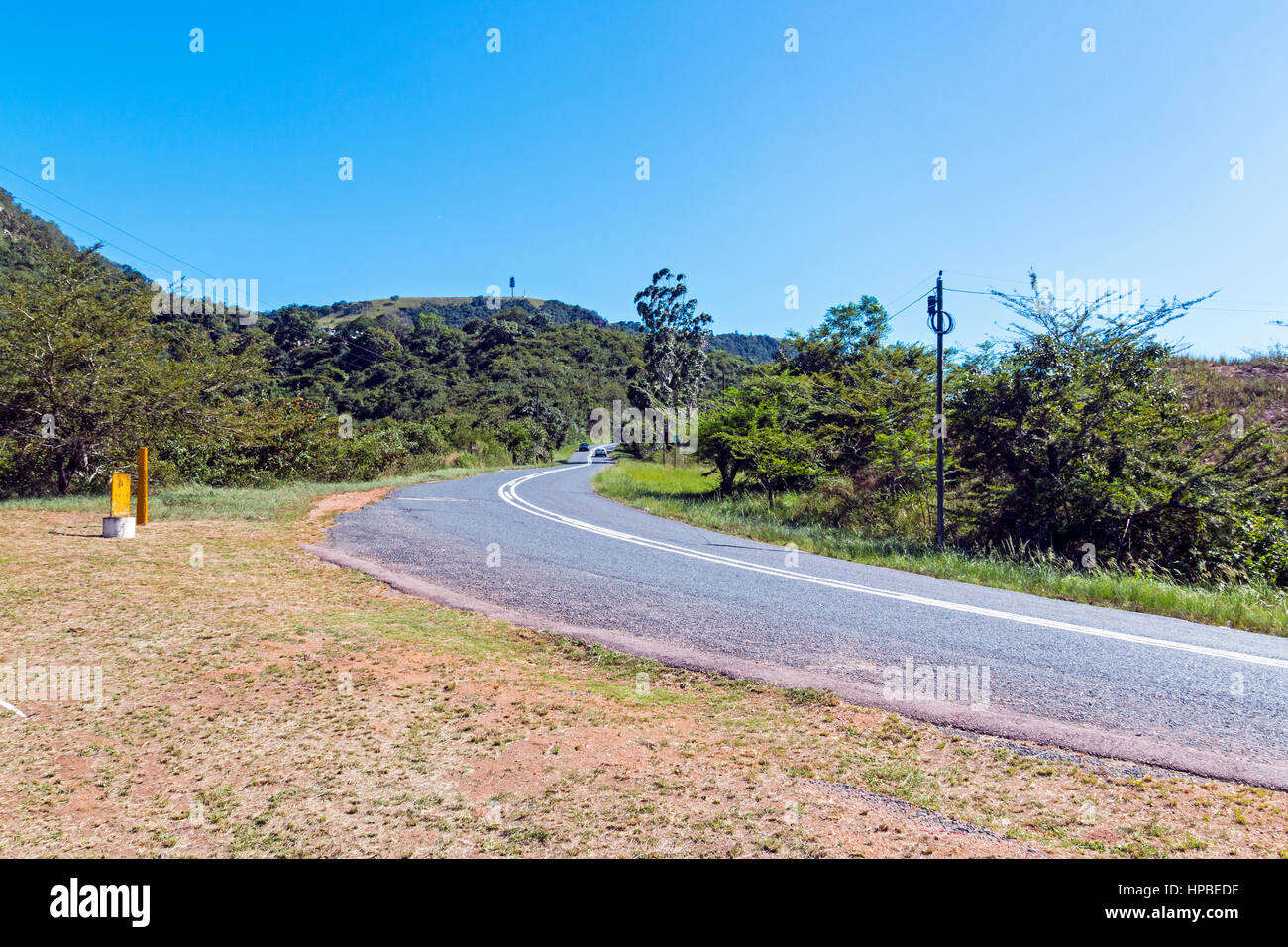 Rural asphalt road curving through green vegetation rural landscape at ...