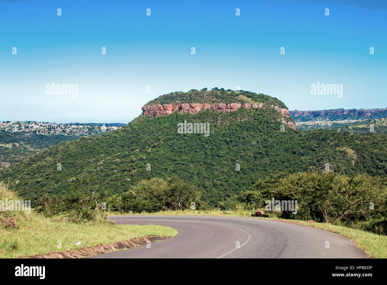 Rural asphalt road curving through green vegetation rural landscape at ...