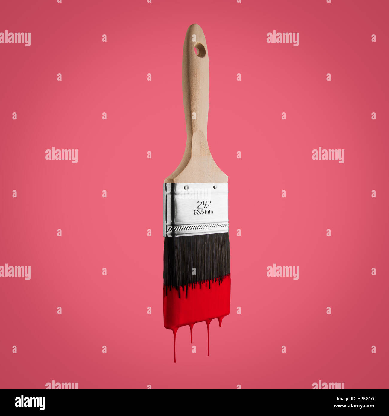 Paintbrush loaded with red color dripping off the bristles, on red ...