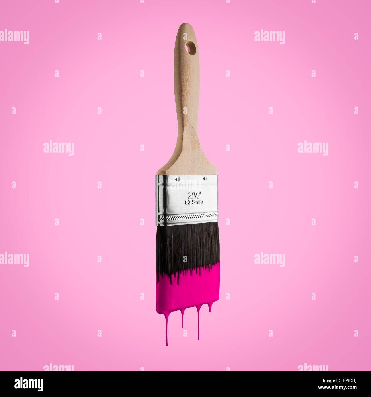 Paintbrush loaded with pink color dripping off the bristles, on pink ...