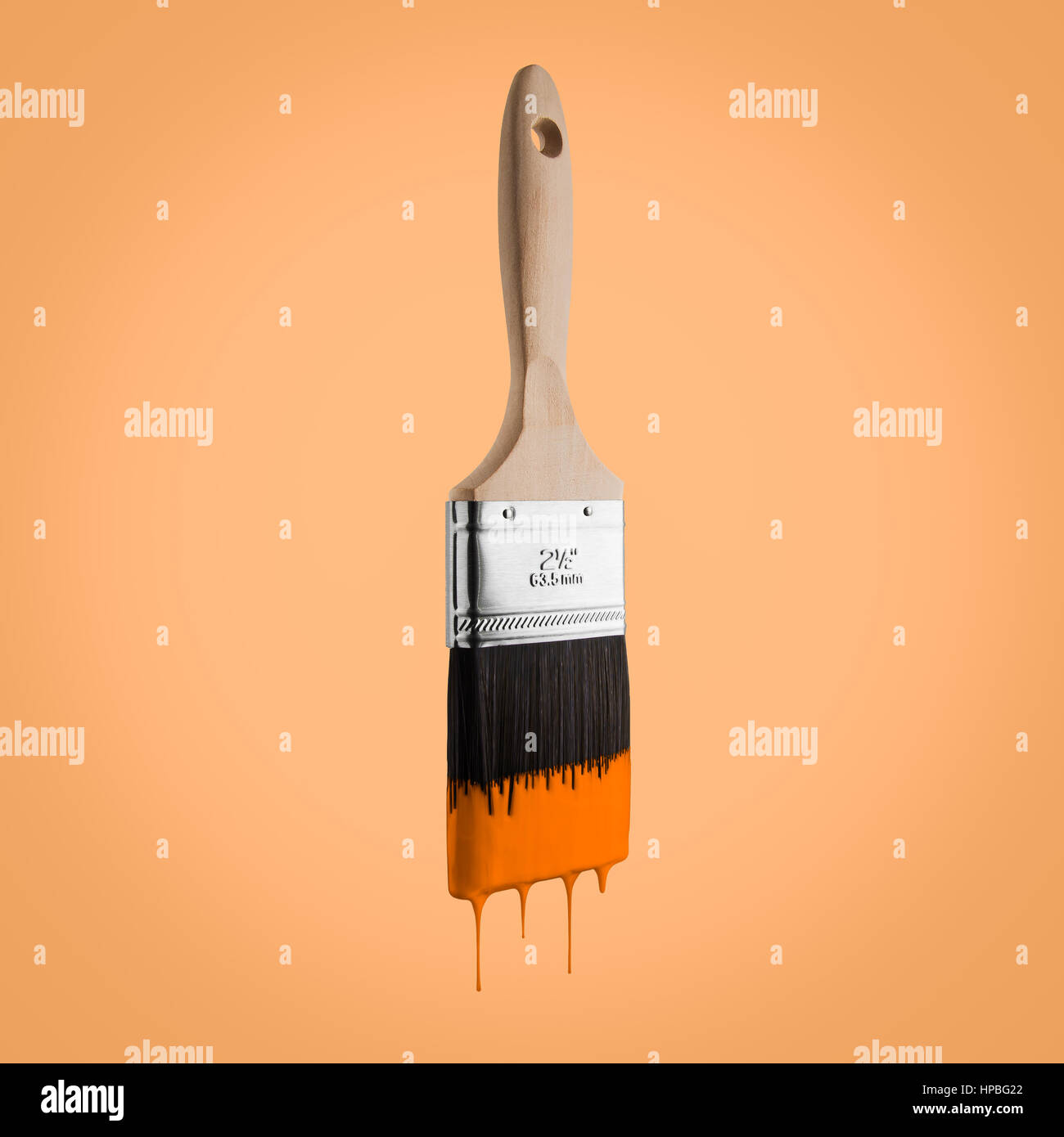 Paintbrush loaded with orange color dripping off the bristles. on ...