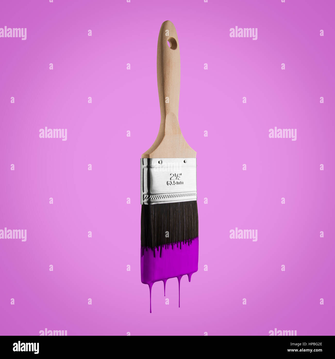 Paintbrush loaded with purple color dripping off the bristles, on ...