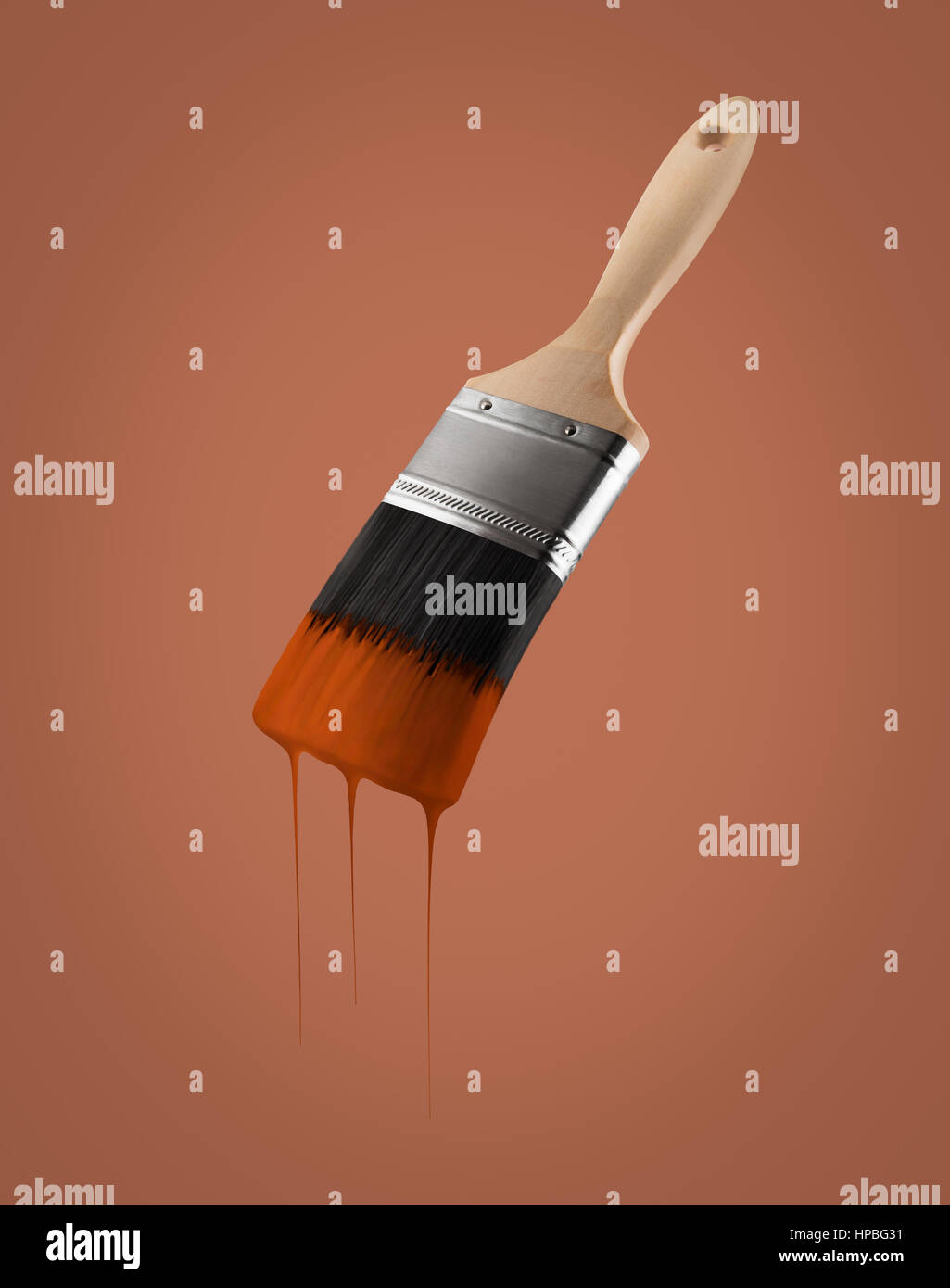 Paintbrush loaded with brown color dripping off the bristles, on brown ...