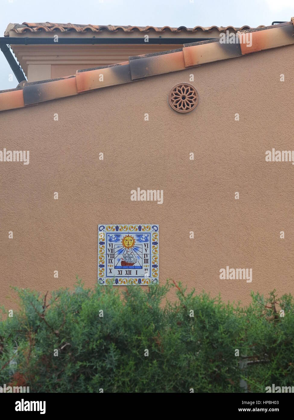 Detail of a brightly painted ceramic sundial on the exterior wall of a ...