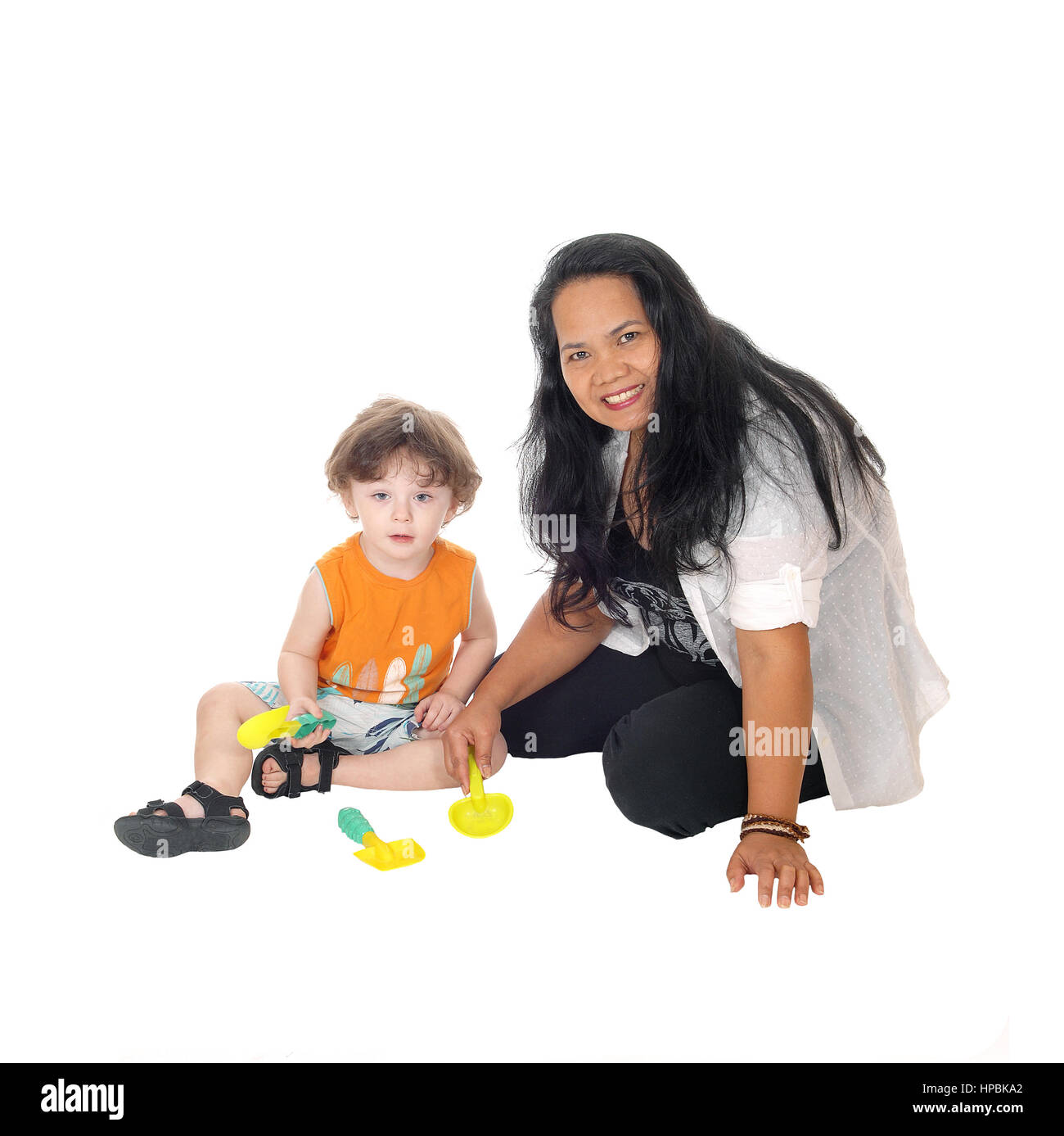 A Filipino nanny sitting on the floor playing with a little three year ...