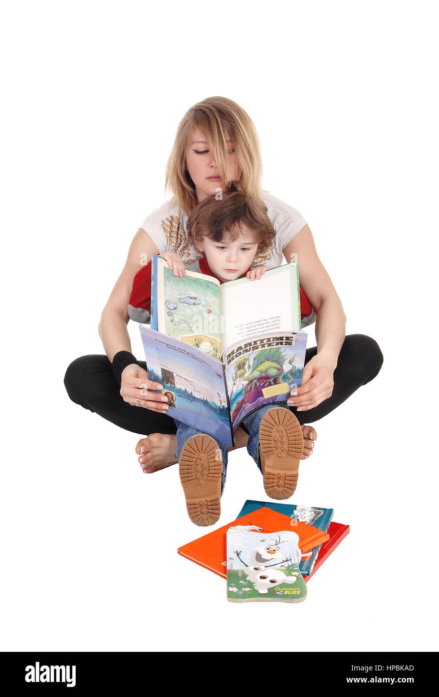 A mother has her little boy on her lap and read some books to him ...