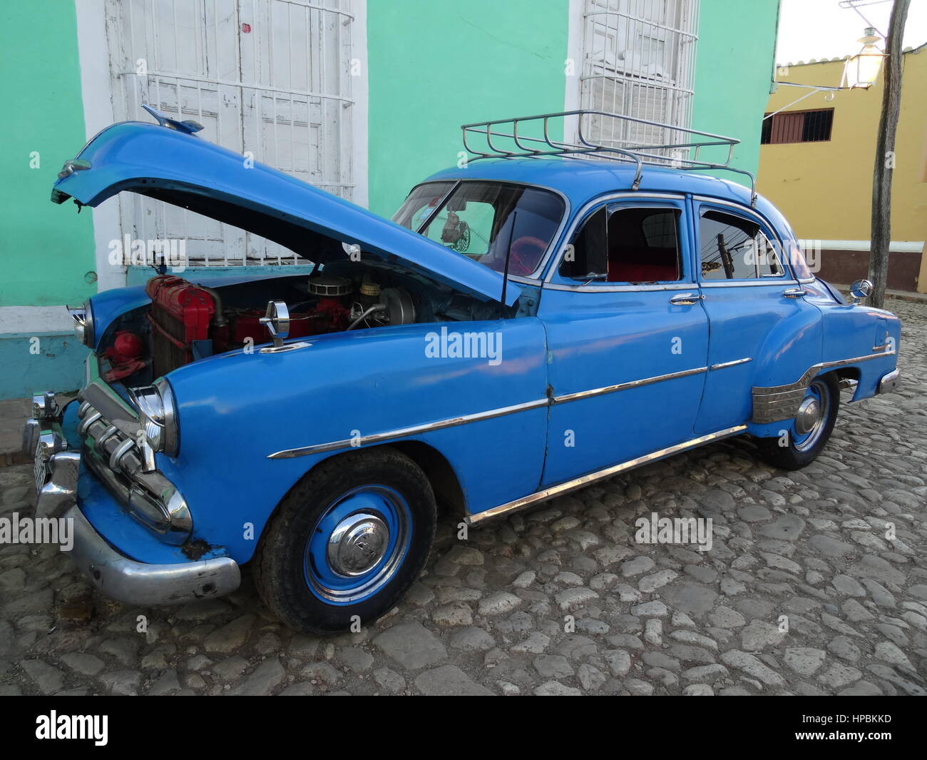 Classic american blue car with open bonnet parked on a cobbled street ...