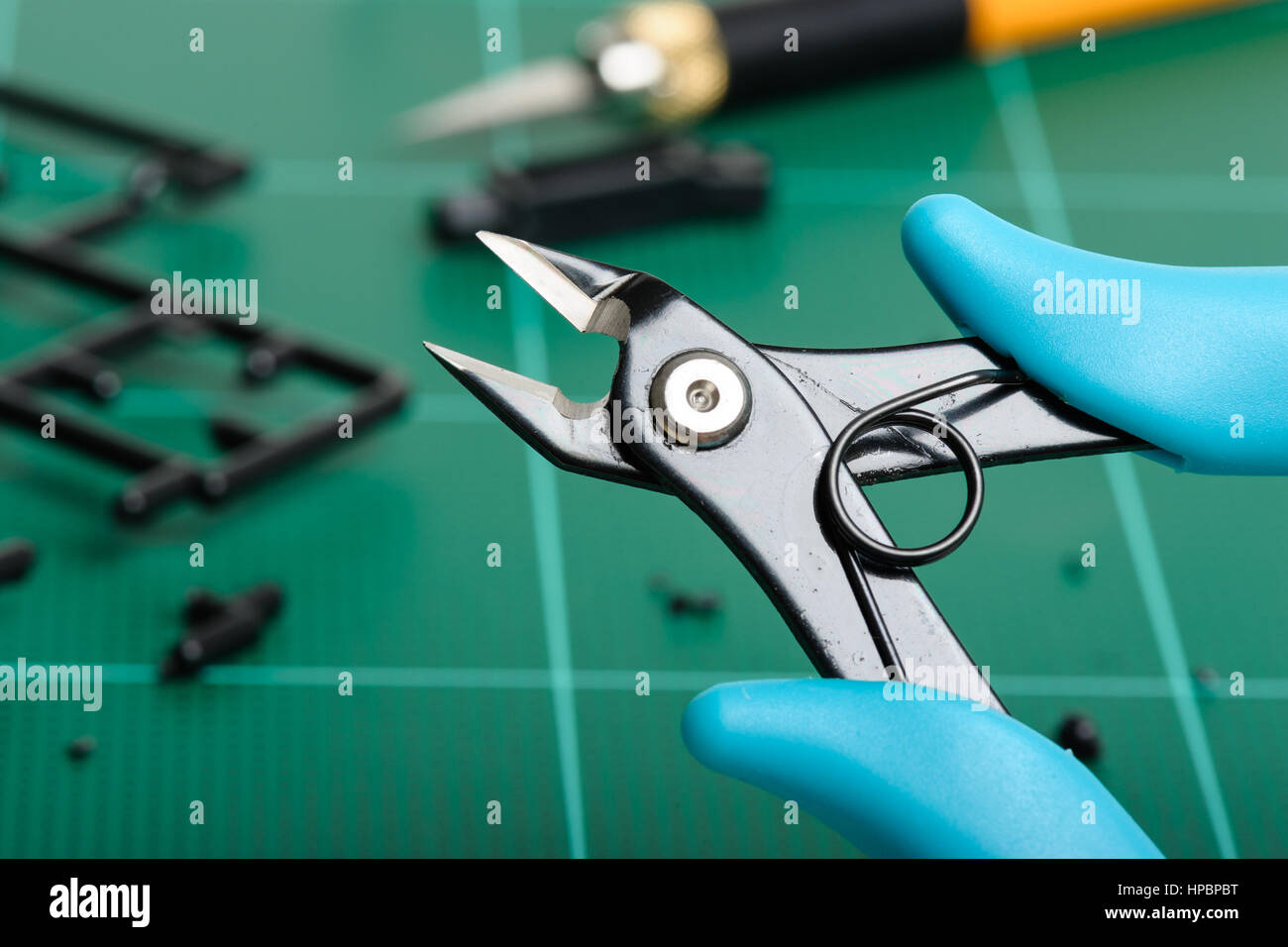 closeup blue plastic nippers over cutting mat Stock Photo - Alamy