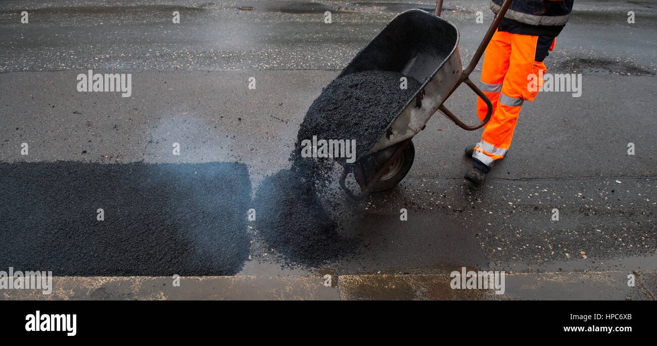 A civil engineering worker filling in potholes on a street in Dresden ...