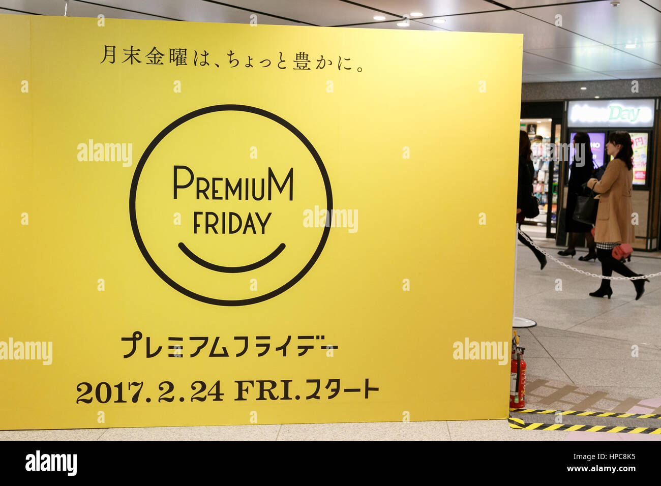 Commuters walk past a Premium Friday signboard on display in Tokyo ...