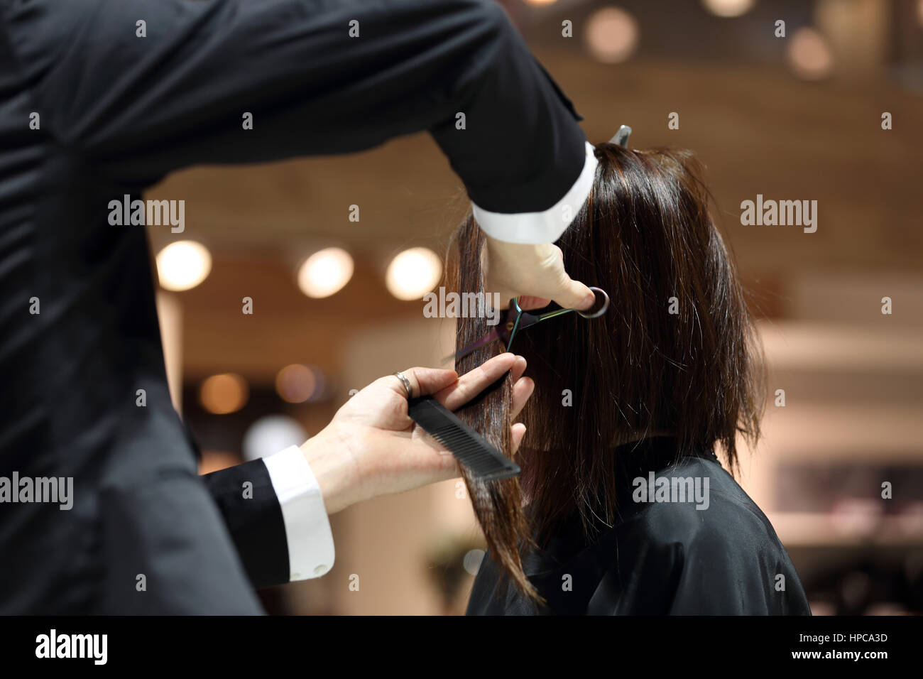 Hairdresser trimming brown hair with scissors Stock Photo - Alamy