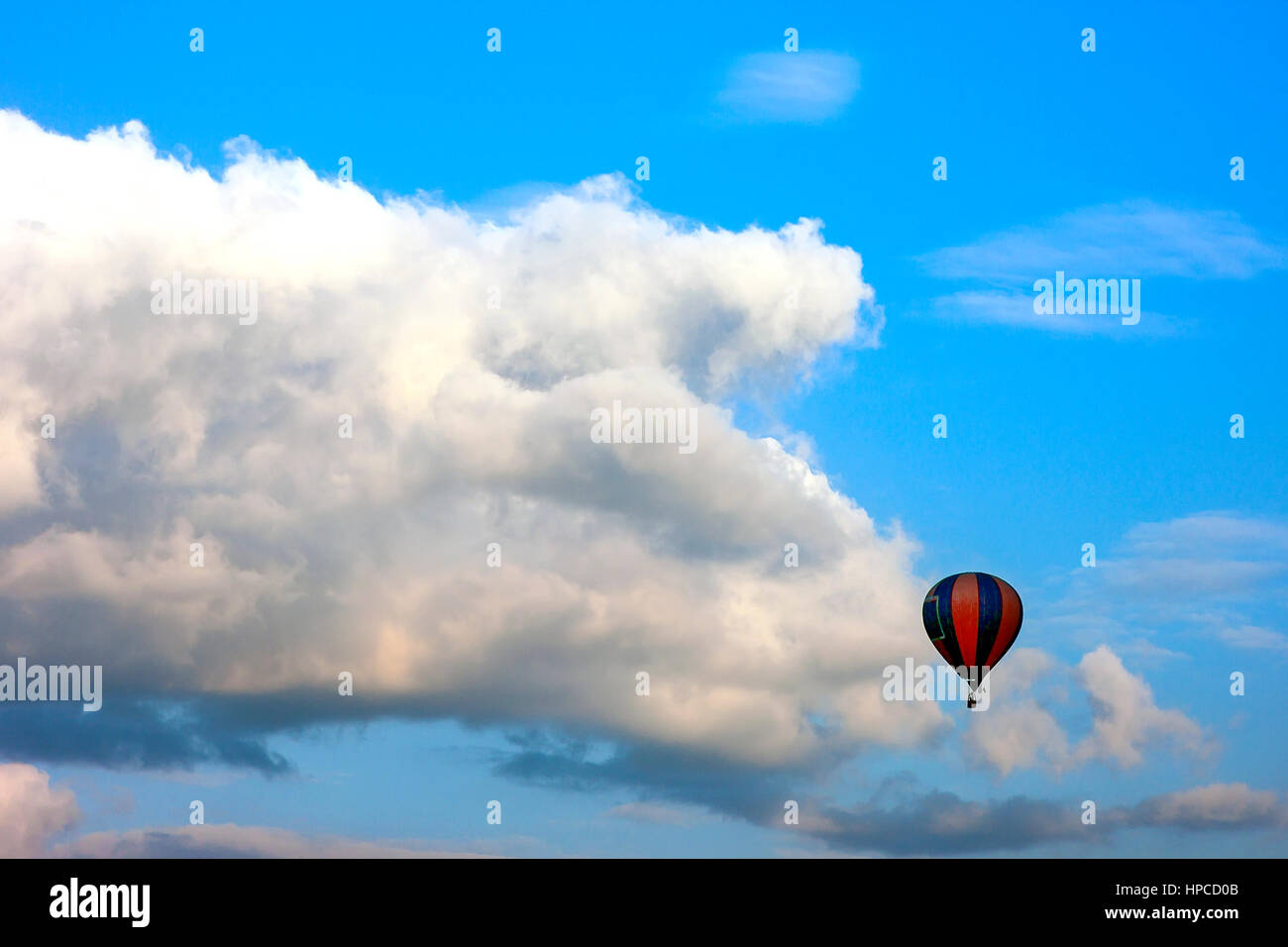 Lonely air baloon flying in front of white puffy clouds against blue ...