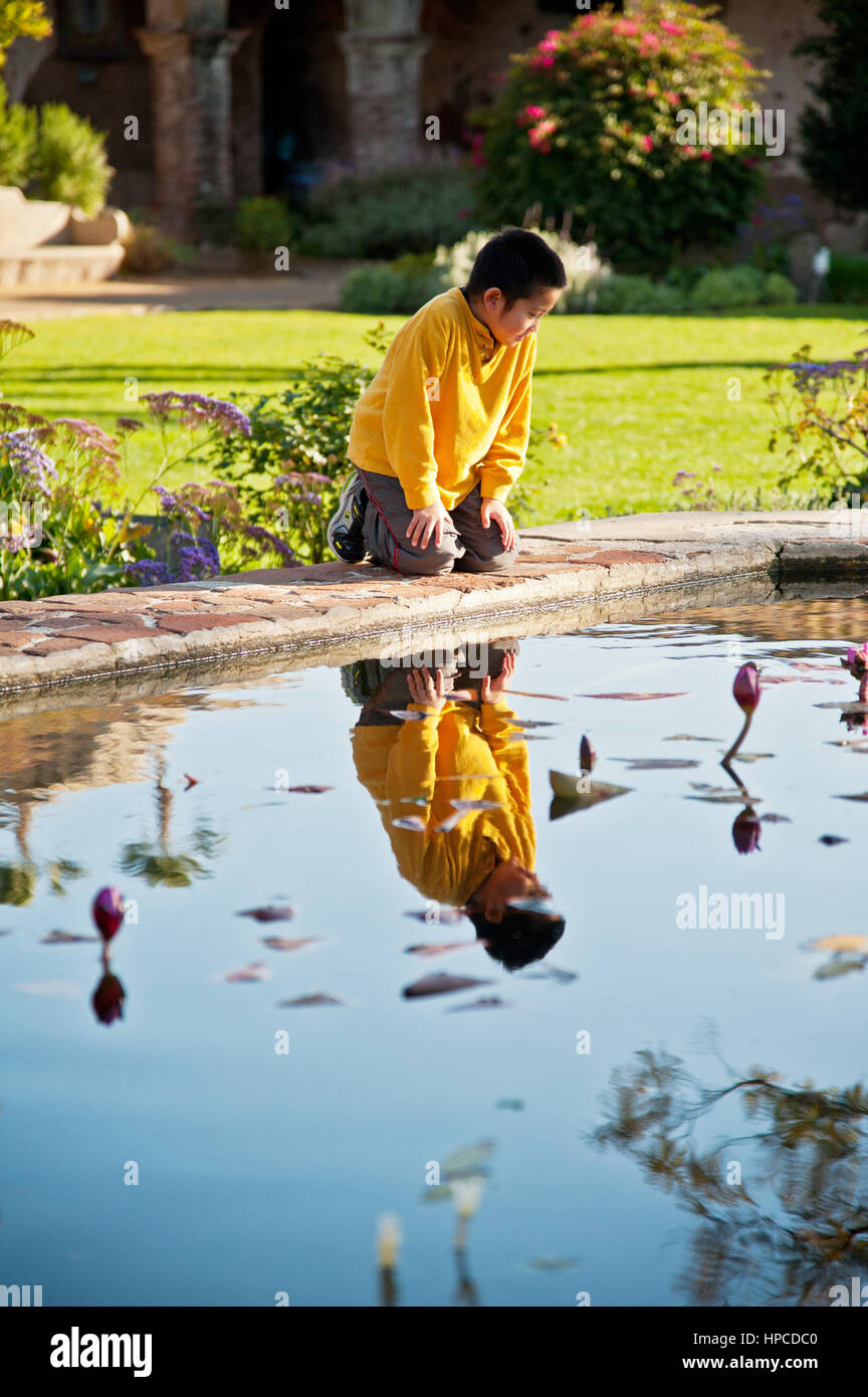 A boy looking at a man made pond Stock Photo - Alamy