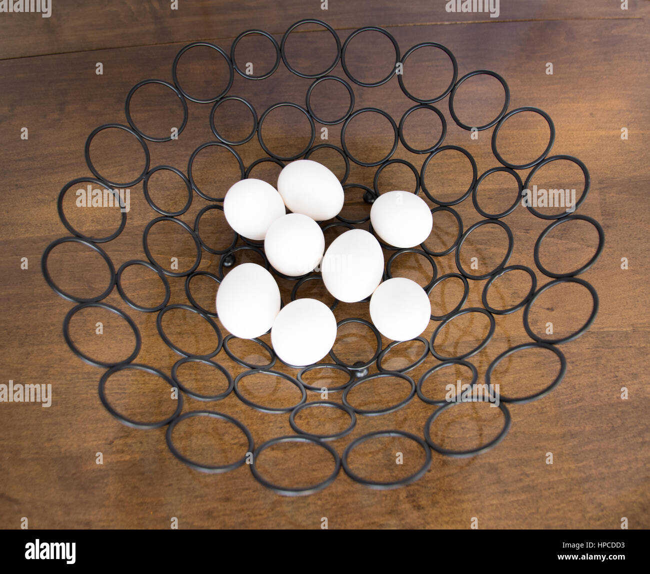 All eight white hen eggs in one black metal basket made from metal ...