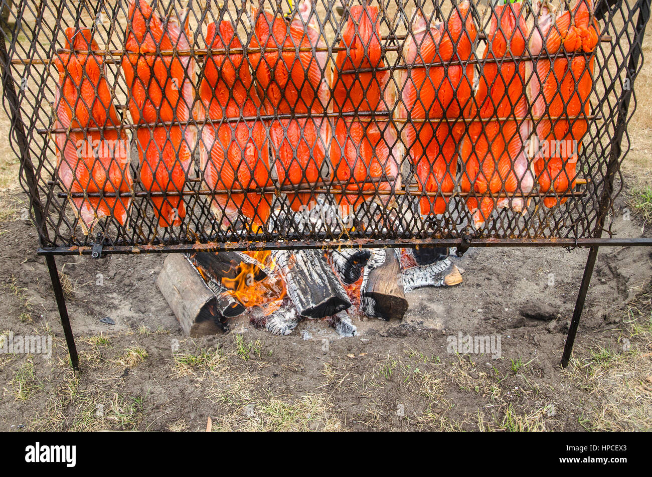 Smoking salmon on rack by fire Stock Photo - Alamy