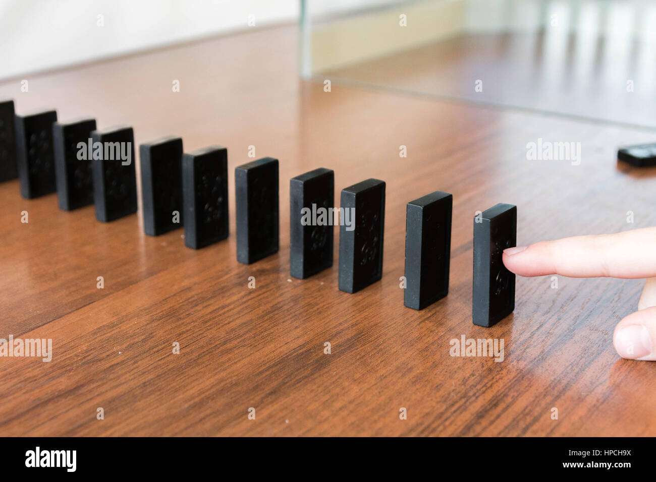 Hand pushing dominoes. Topple track of dominoes Stock Photo - Alamy