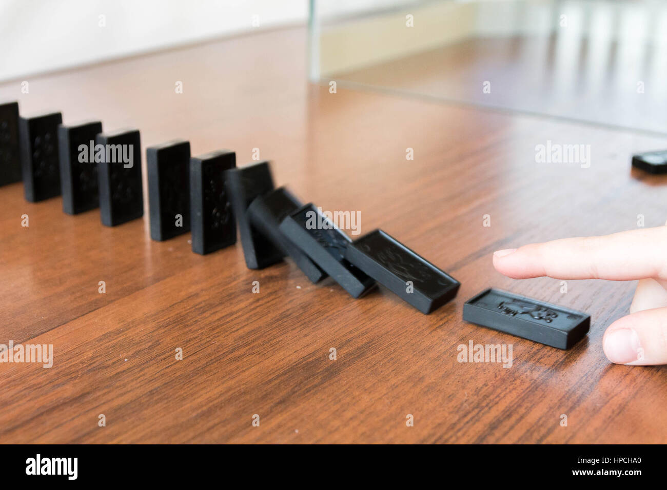 Hand pushing dominoes. Topple track of dominoes Stock Photo - Alamy