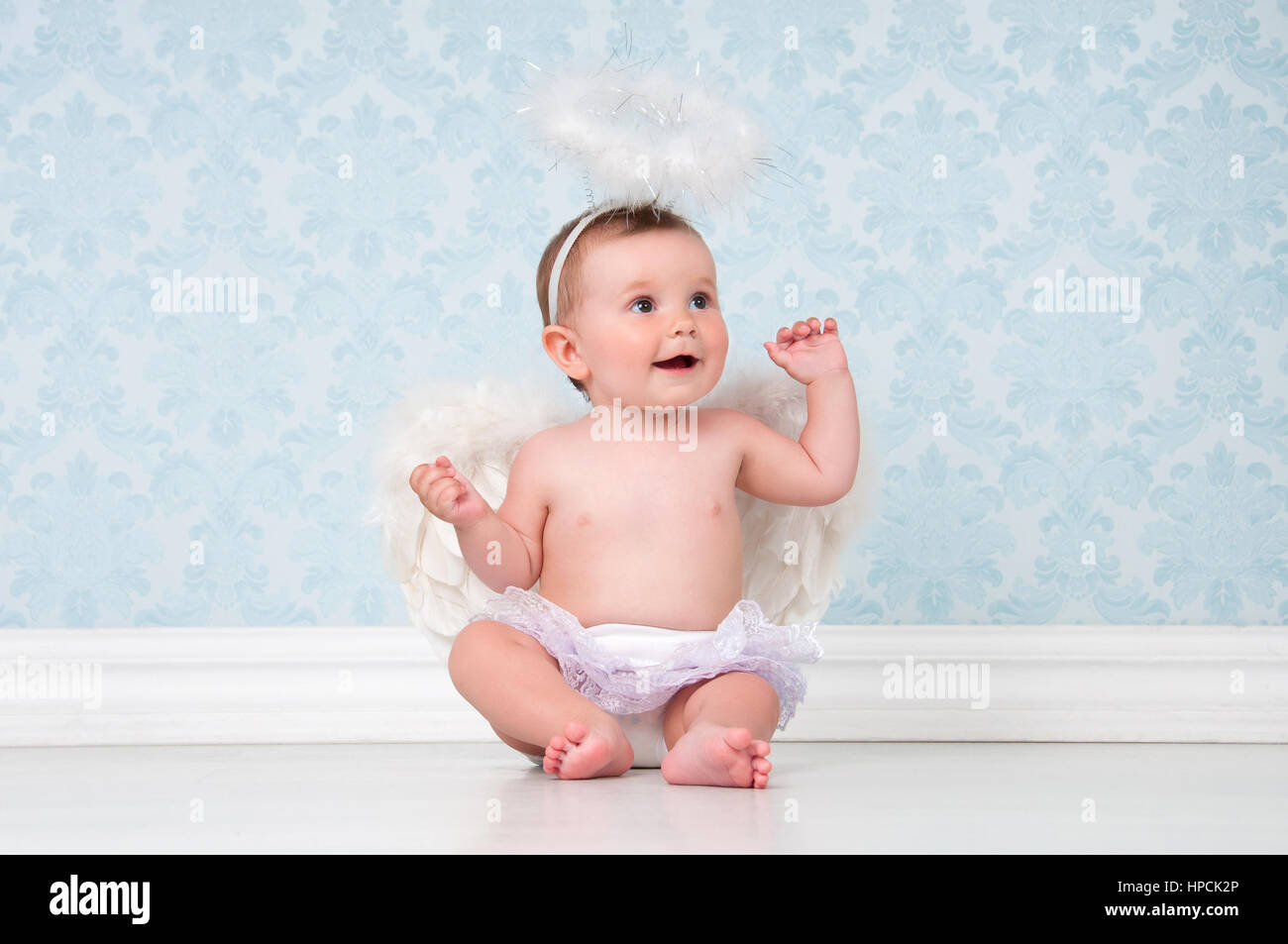 Little angel smiling and sitting on the floor Stock Photo - Alamy