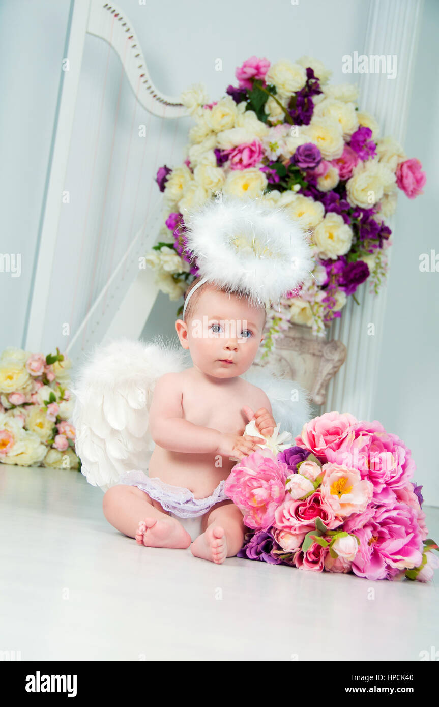 Little angel smiling and happy sitting on the background of flowers and ...