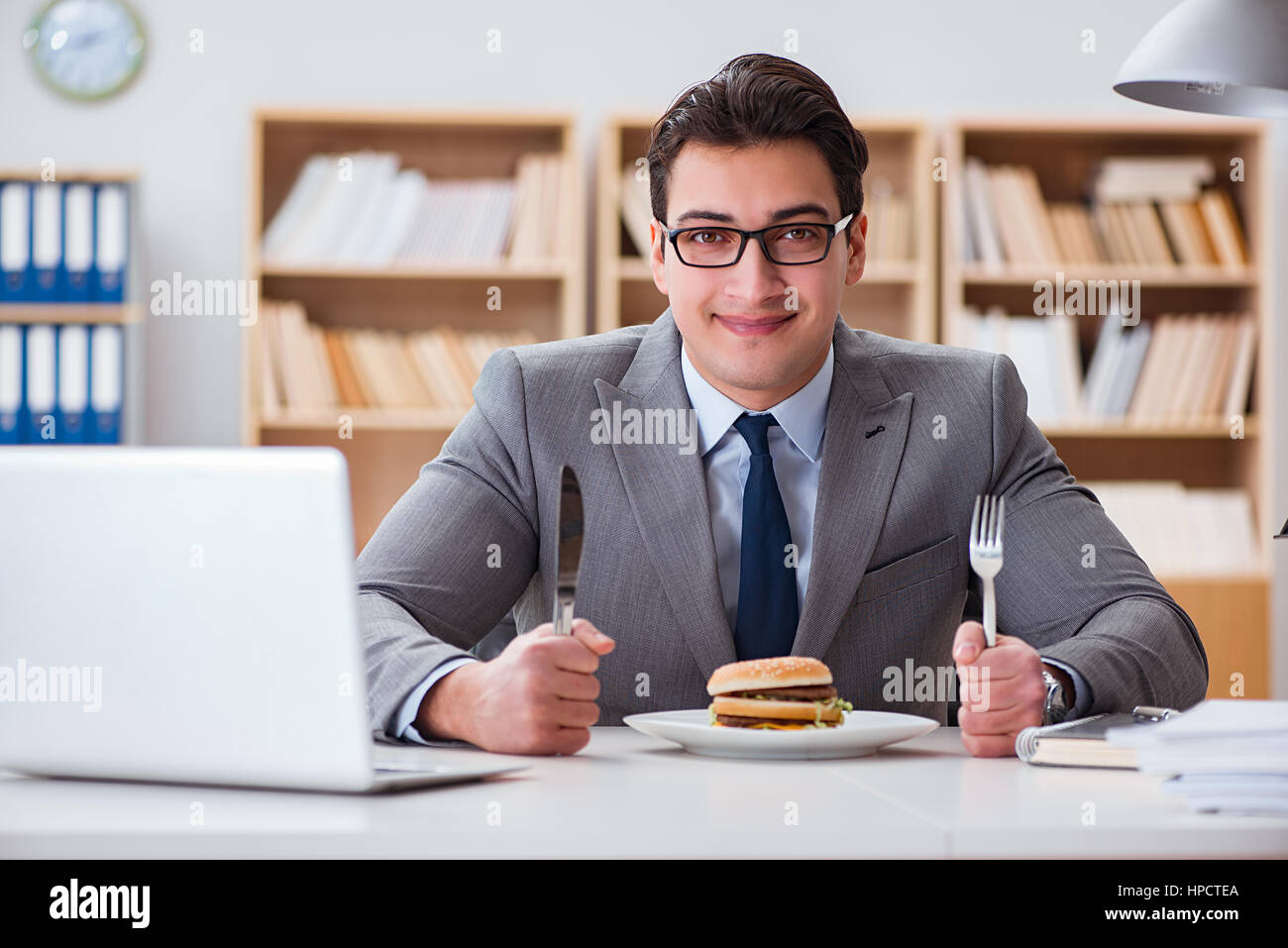 Hungry funny businessman eating junk food sandwich Stock Photo - Alamy