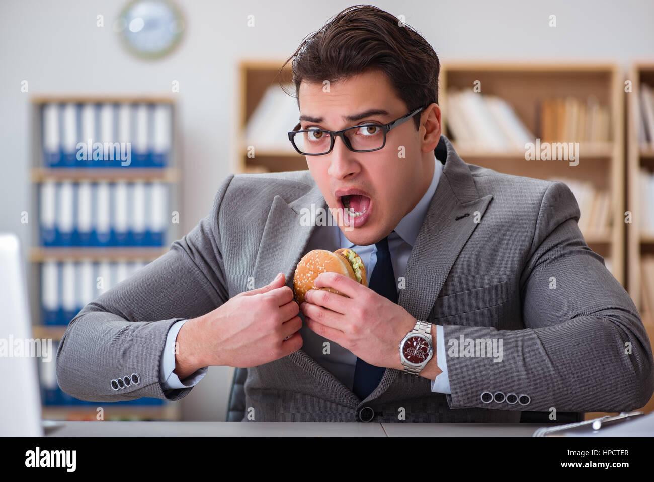Hungry funny businessman eating junk food sandwich Stock Photo - Alamy