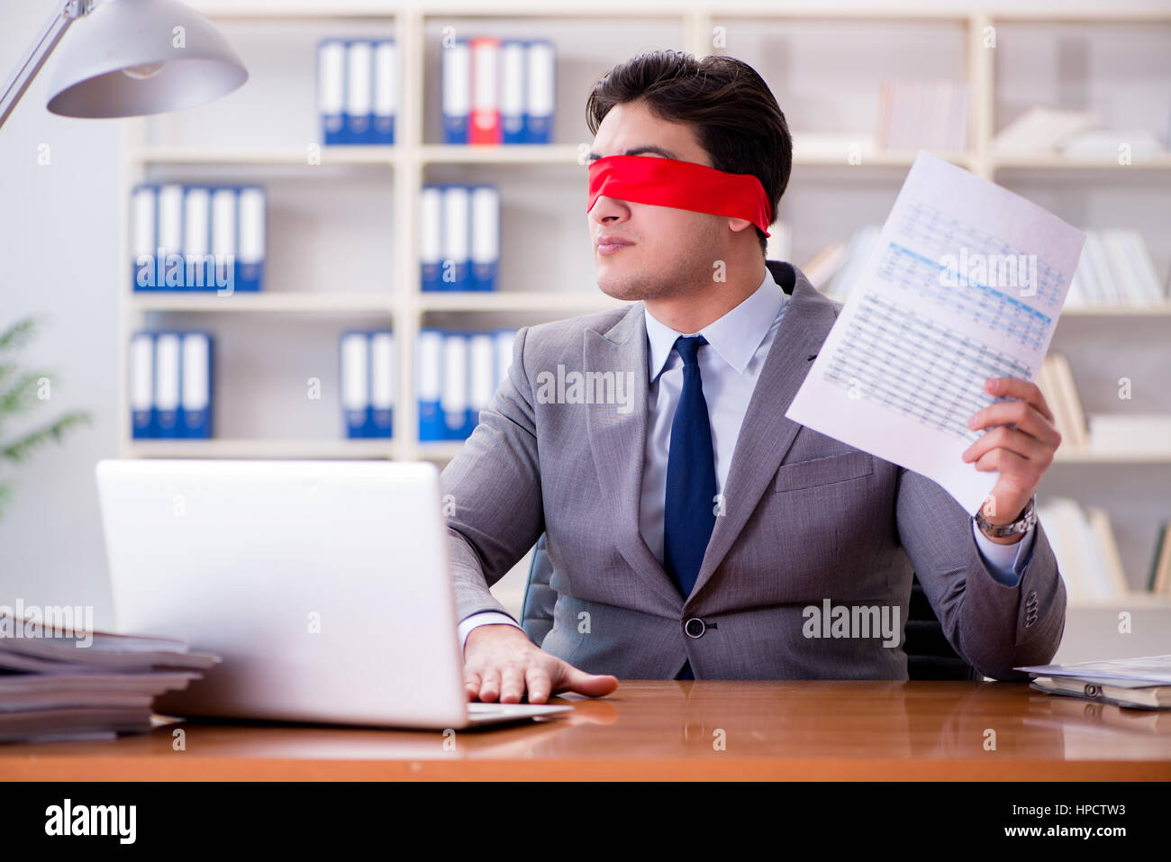 Blindfold businessman sitting at desk in office Stock Photo - Alamy