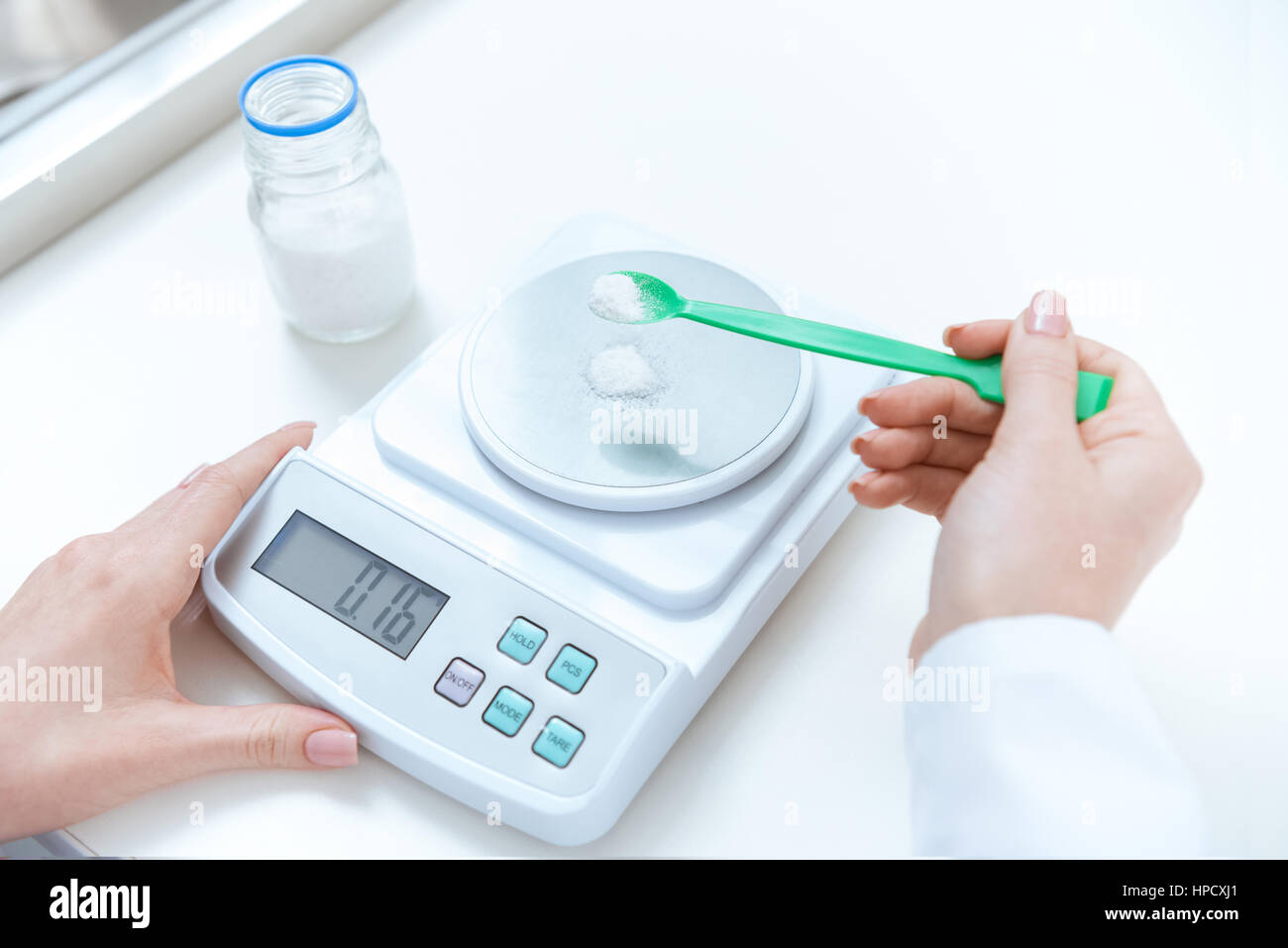 Close-up partial view of chemist weighing reagent on laboratory scales ...