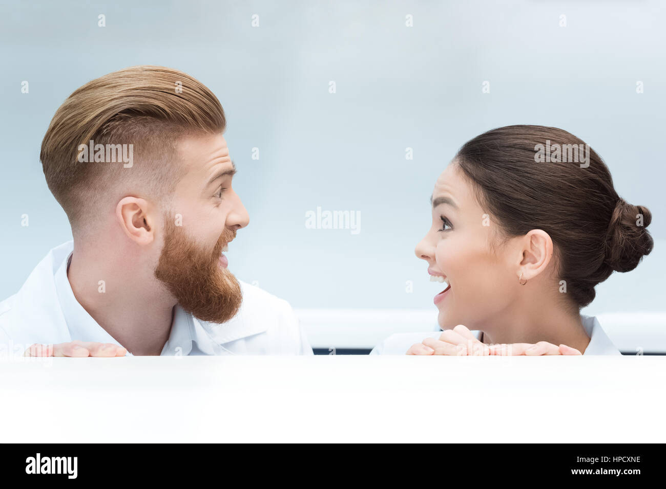 portrait of excited scientists looking at each other behind table in ...