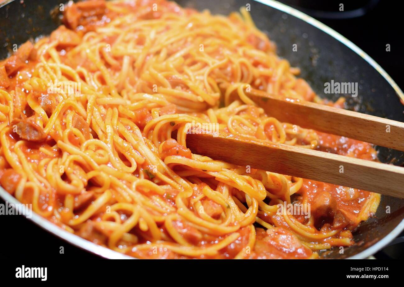 Cooking the spaghetti with red tomato sauce and sausage. Stirring ...