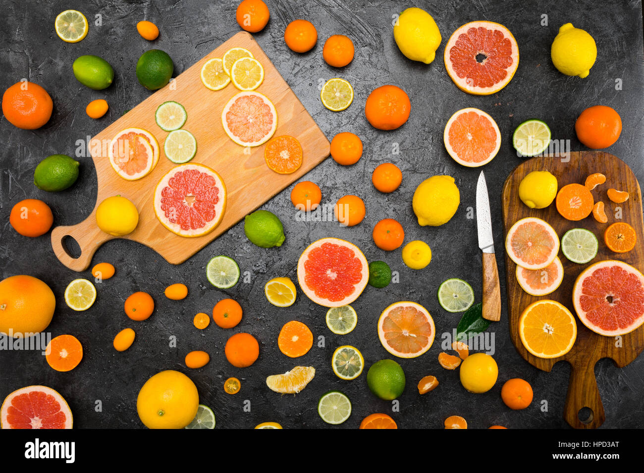 top view of various fresh whole and sliced citrus fruits on cutting ...