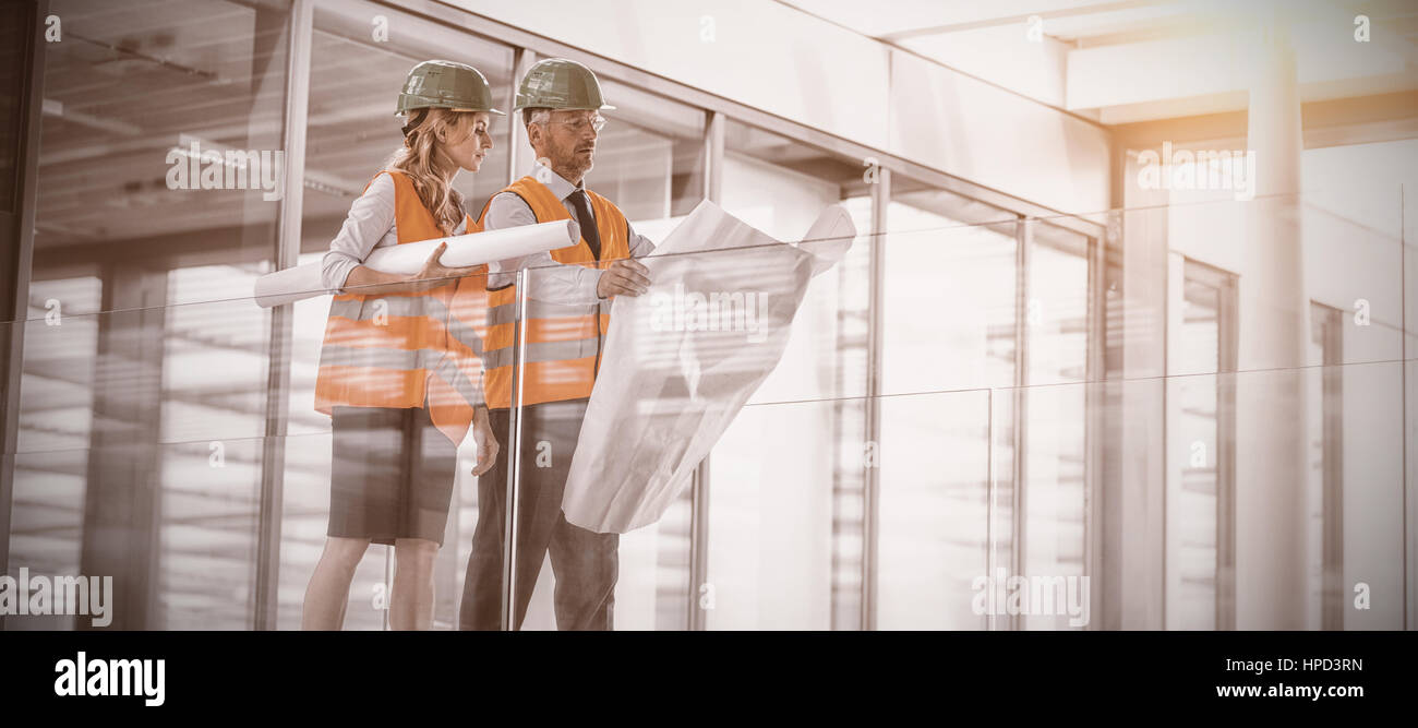 Architects discussing with blueprint in office corridor Stock Photo - Alamy
